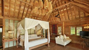 Quarto espaçoso com uma cama grande, um sofá, uma televisão e um ventilador de teto.