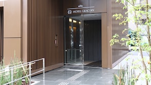 Uma entrada de hotel moderna com uma placa visível que diz "WHG HOTEL GRACERY".