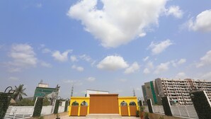 Um edifício com um grande portão de entrada, rodeado de vegetação e sob um céu claro.