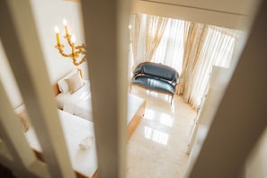 Quarto com uma cama branca, um sofá azul e um candelabro.