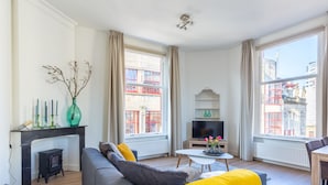 Sala moderna com sofá, uma mesinha, lareira e grandes janelas com vista para a cidade.
