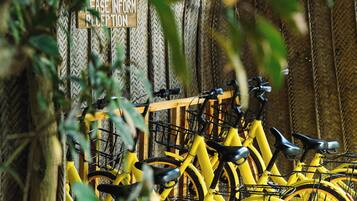 Uma fileira de bicicletas amarelas estacionadas em área protegida, com uma placa indicando a receção.
