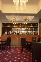 Uma área de bar com um bartender, variedade de garrafas de bebidas e um tapete estampado.
