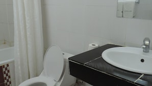 Um banheiro com vaso sanitário branco, pia preta, espelho e cortina de chuveiro.