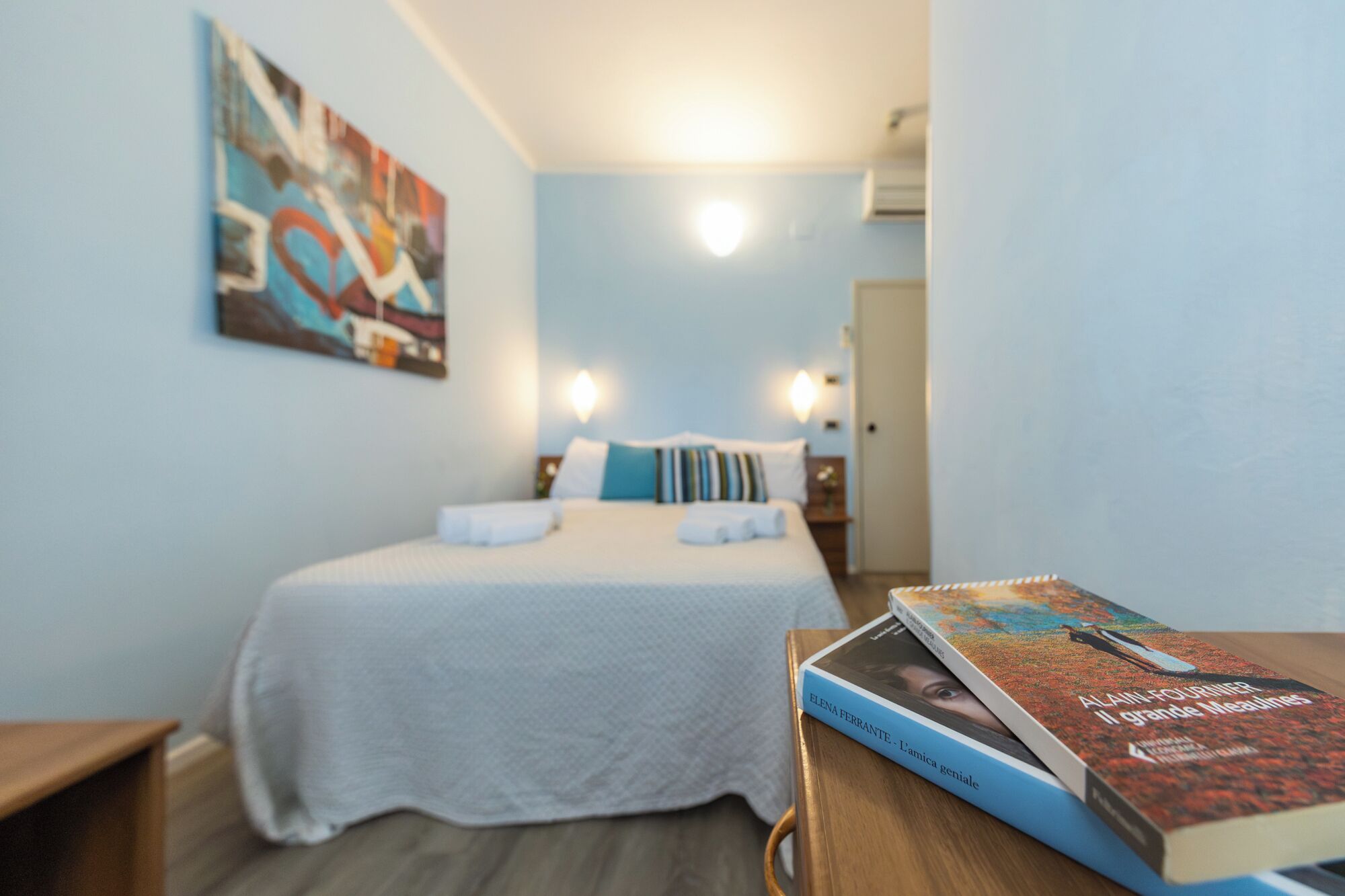 Quarto com cama, mesas de cabeceira e um livro em uma mesinha de noite.