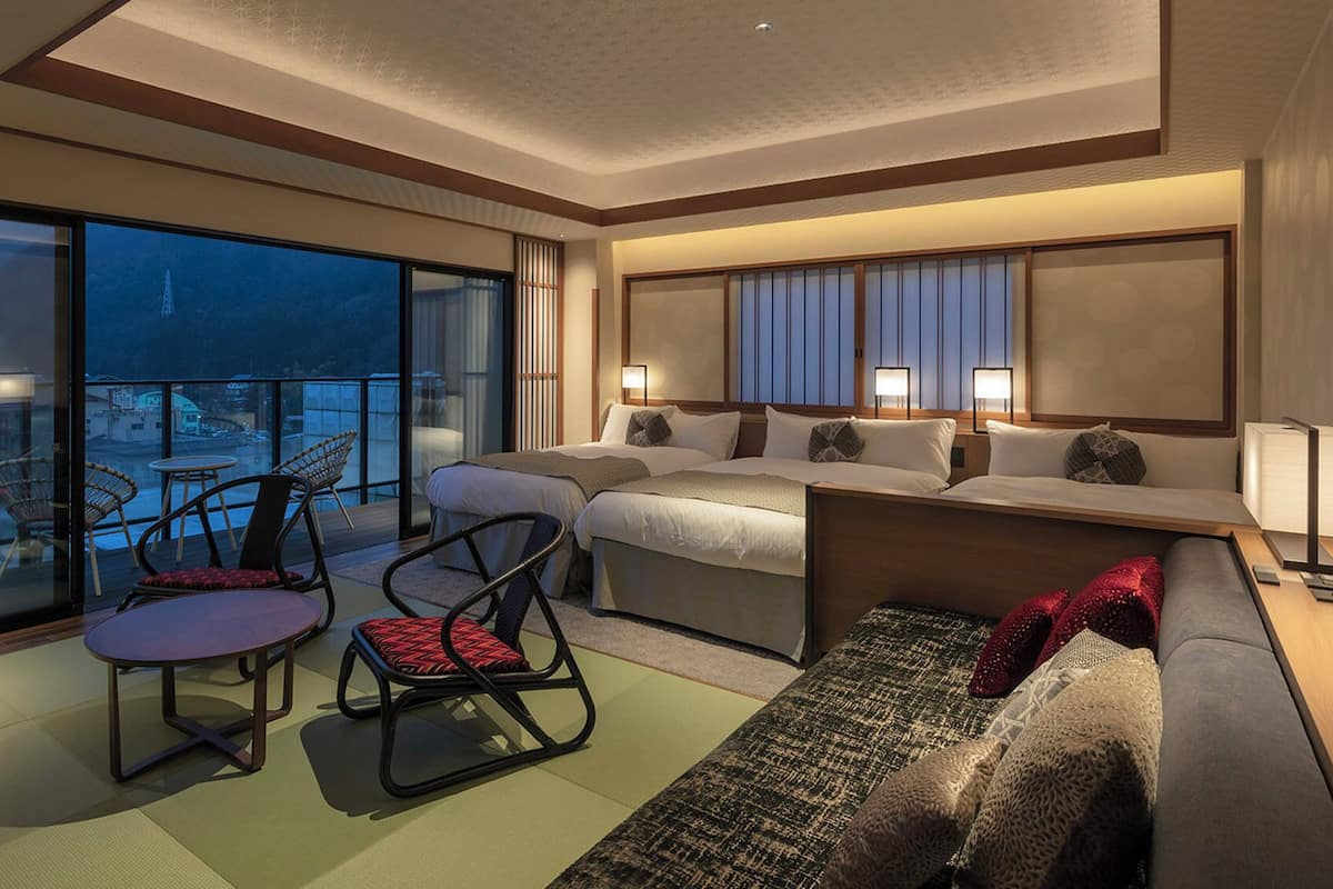 Quarto de hotel com varanda, duas camas, um sofá e uma mesa de jantar.