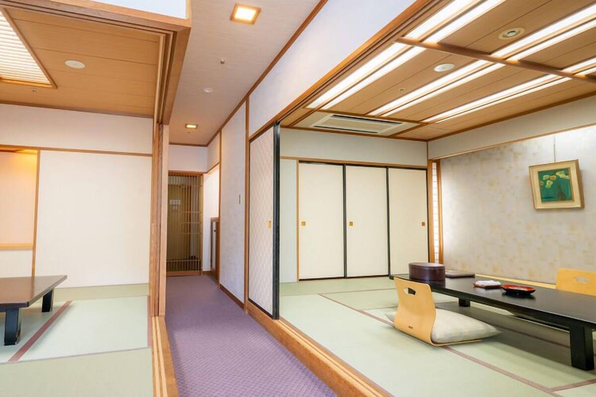 Um quarto japonês tradicional com tatames, portas deslizantes, uma mesa baixa e um assento almofadado.