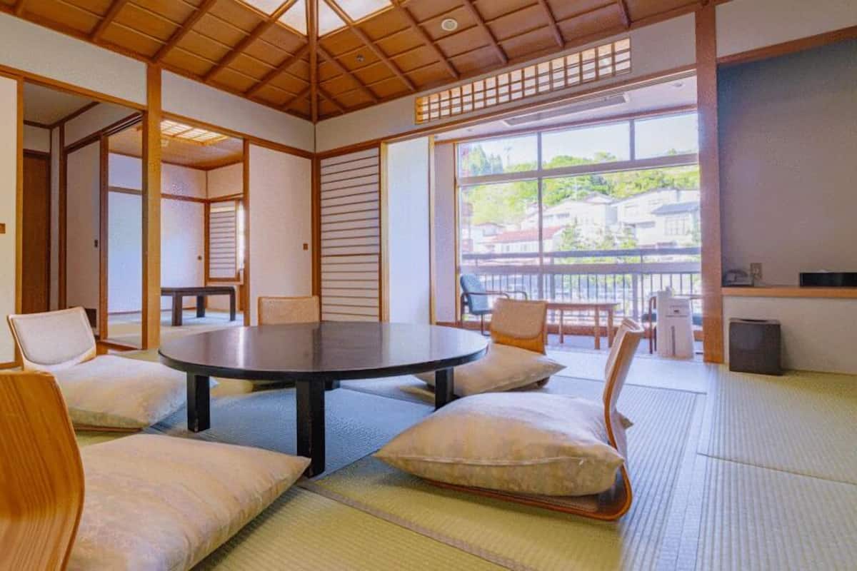 Um quarto em estilo japonês tradicional, com tatames, uma mesa redonda e mobiliário de madeira baixo.