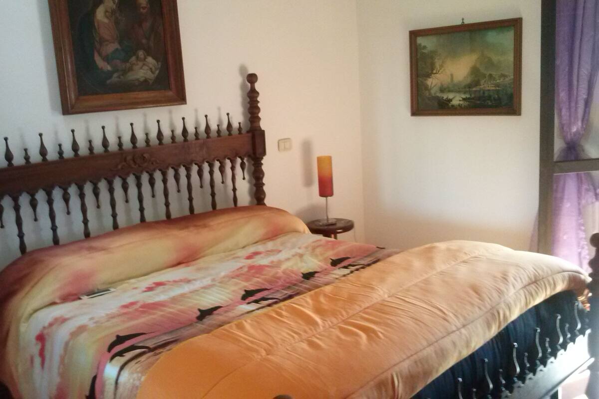 Quarto com cabeceira de madeira, colcha florida e duas obras de arte emolduradas na parede.