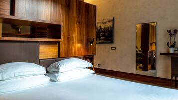 Quarto de hotel com uma cama grande, cabeceira de madeira, estantes embutidas, um espelho e um quadro na parede.