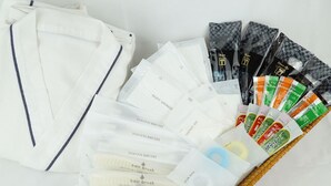 Um conjunto de artigos de higiene pessoal, incluindo uma camisa branca, esponja para o corpo e vários pentes de cabelo.