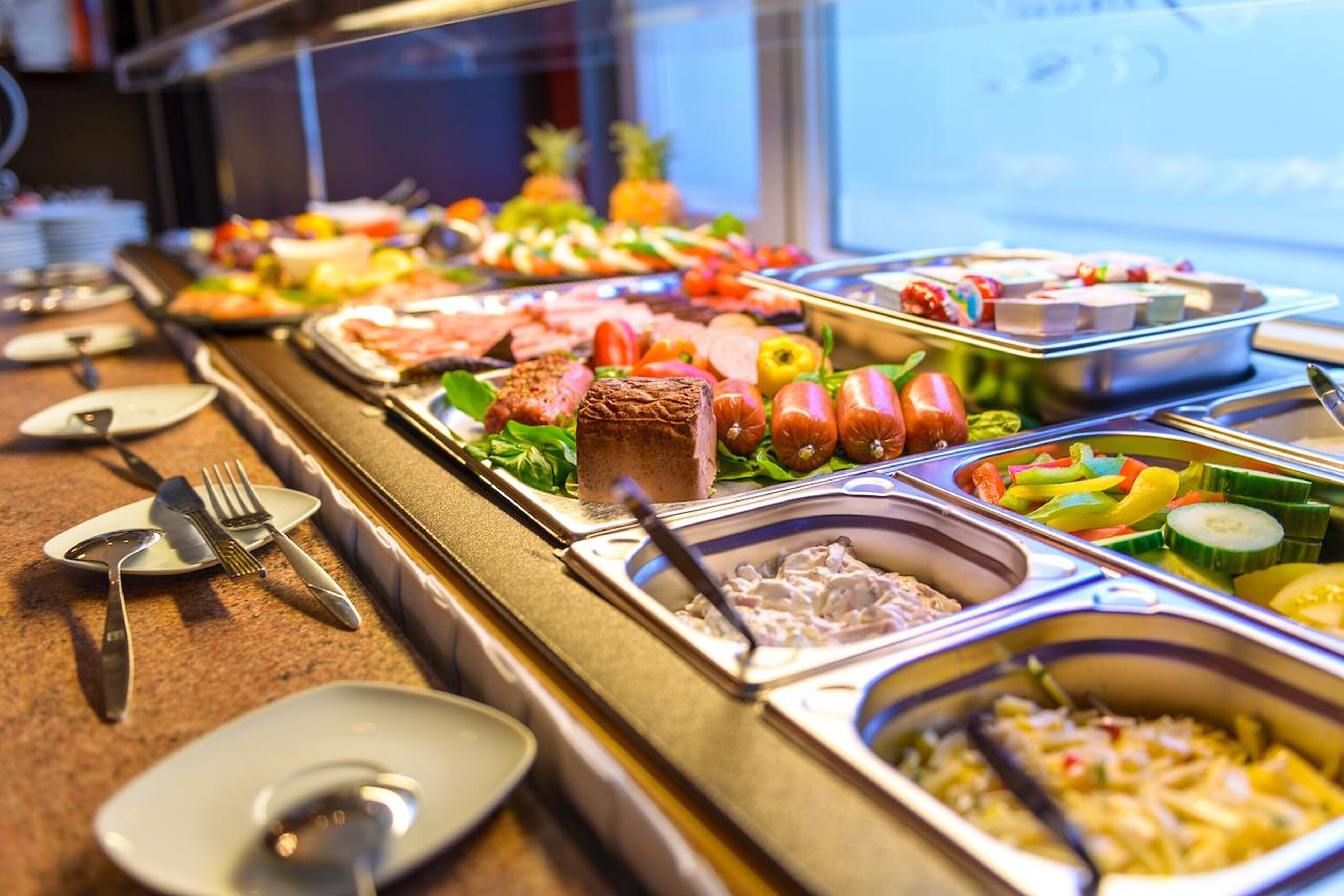 Um buffet com diversas opções de comida, incluindo carnes, frutas e legumes.