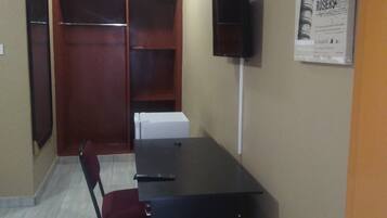 Uma sala de conferência com mesa preta, cadeira vermelha, quadro branco e um cartaz na parede.
