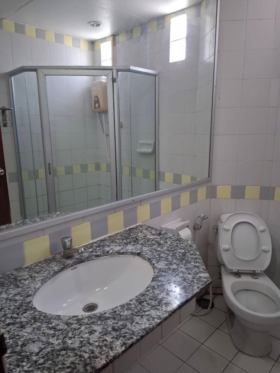 Casa de banho com lavatório de granito, sanita e cabine de duche.