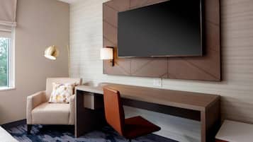 Quarto de hotel moderno com uma grande TV de tela plana na parede, uma escrivaninha com cadeira e uma janela com vista para o exterior.
