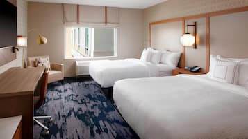Quarto de hotel com duas camas, uma escrivaninha, uma cadeira, uma televisão e uma janela com vista.