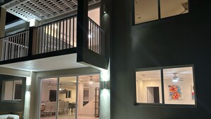 Um interior espaçoso com varanda, área de jantar e sala de estar com uma janela grande e obras de arte.