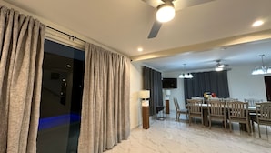 Uma sala de estar moderna com área de jantar, ventilador de teto e TV na parede.