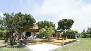 Uma casa com um pátio, móveis de exterior e árvores.