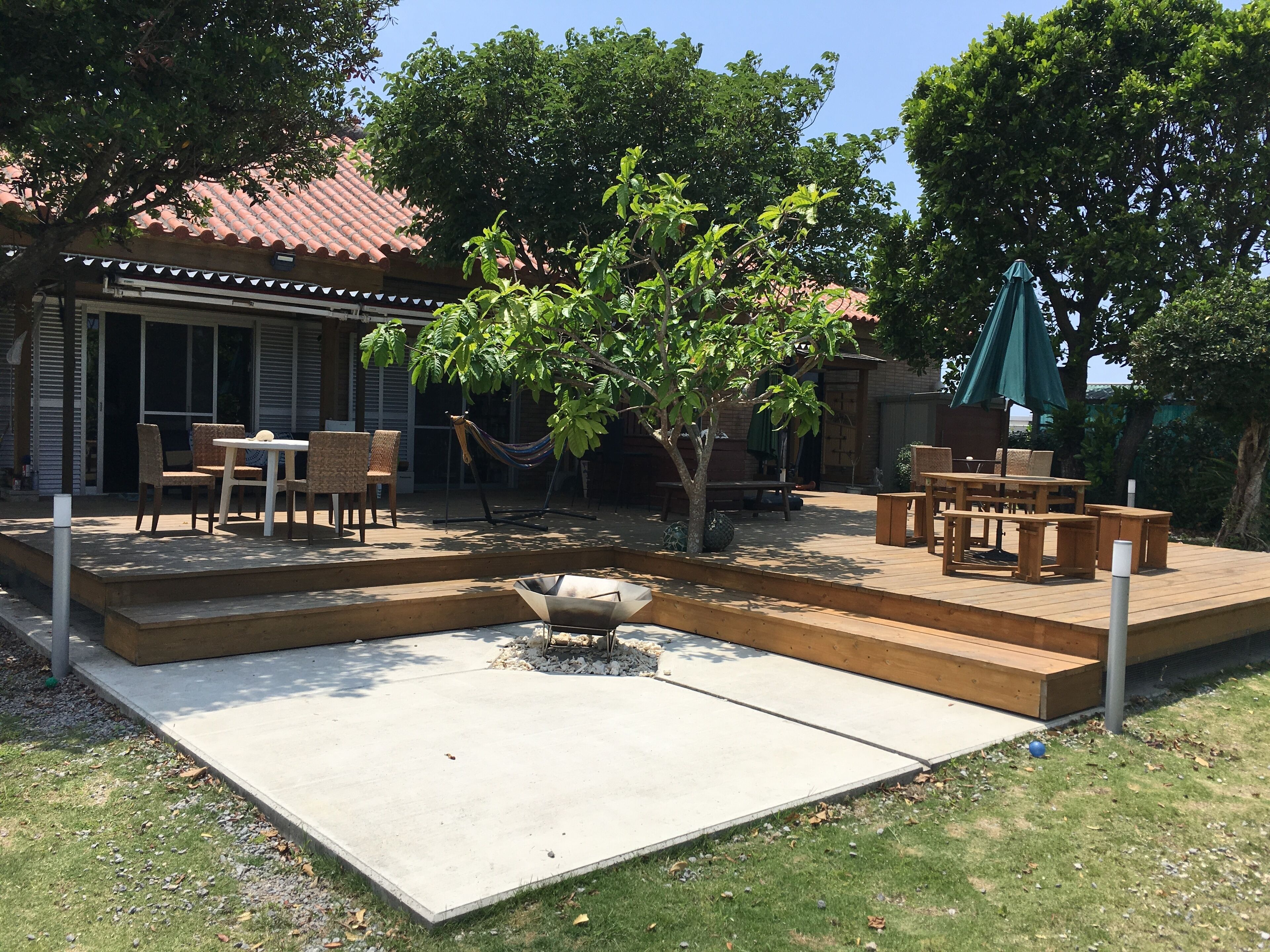 Um pátio com deck de concreto, móveis de exterior e uma rede.