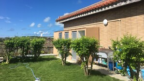 Uma casa com telhado de telhas, antena parabólica e gramado com árvores.