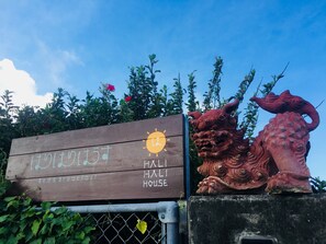 Uma placa de madeira com a inscrição 'Bed & Breakfast' e 'FALL HALL HOUSE', ao lado de uma estátua decorativa de um leão vermelho.