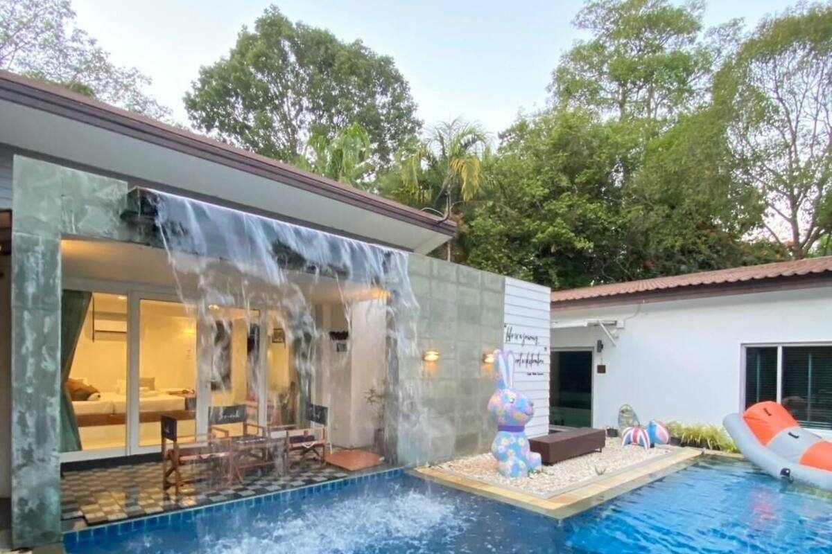 Uma piscina com uma cascata, área de estar e uma piscina insuflável pequena.
