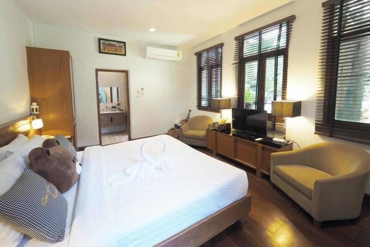 Quarto de hotel com cama, televisão, sofá e escrivaninha.