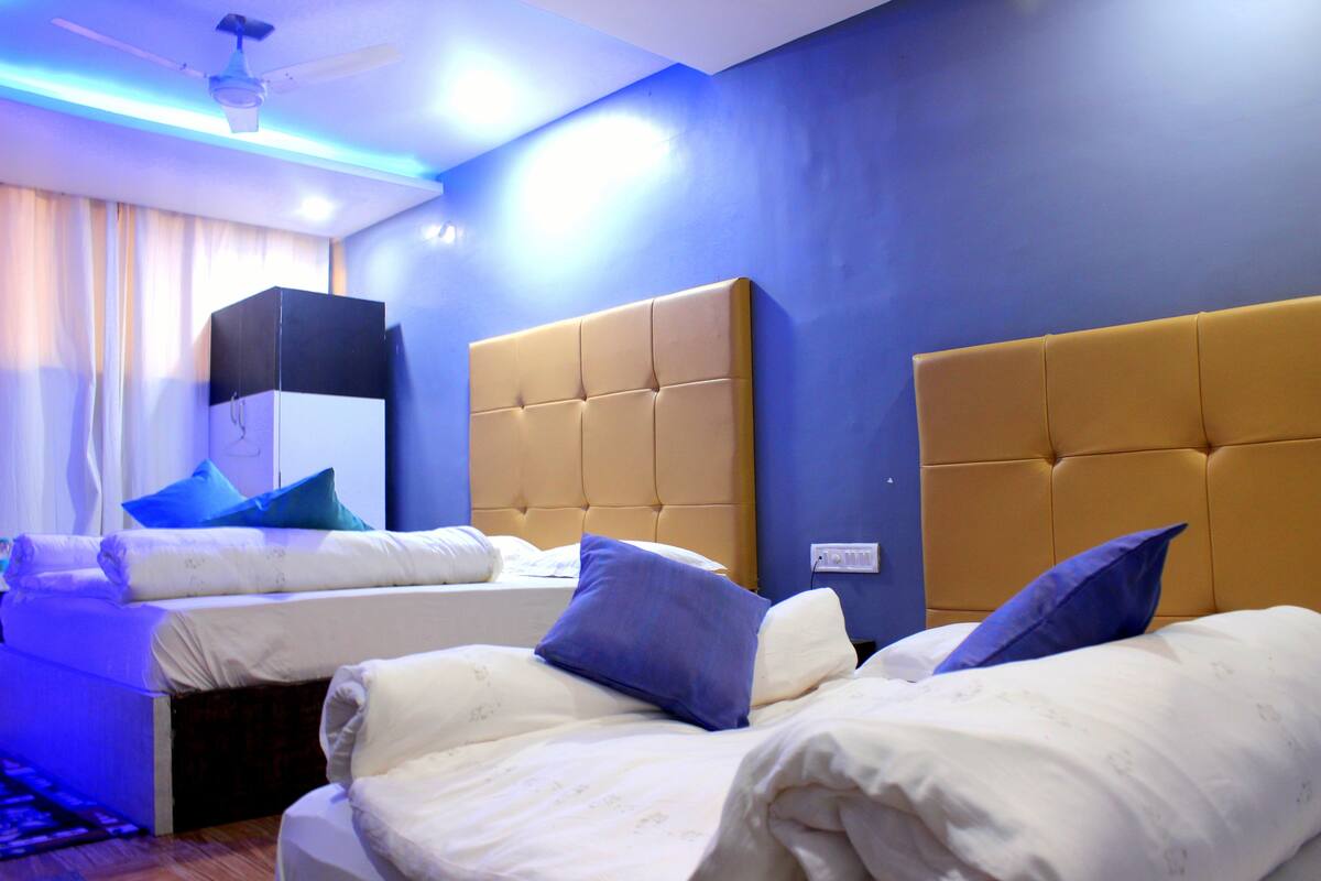 Quarto de hotel com duas camas, um ventilador de teto e uma mesa de cabeceira.