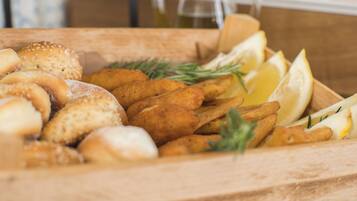 Uma bandeja de madeira com diversos alimentos fritos, incluindo itens empanados e fatias de limão.