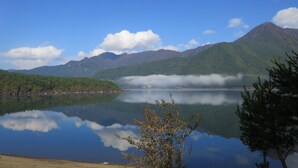 Um lago calmo com montanhas ao fundo e céu claro.