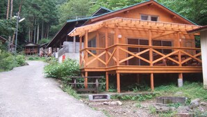 Uma cabana de madeira com varanda, rodeada por uma floresta.