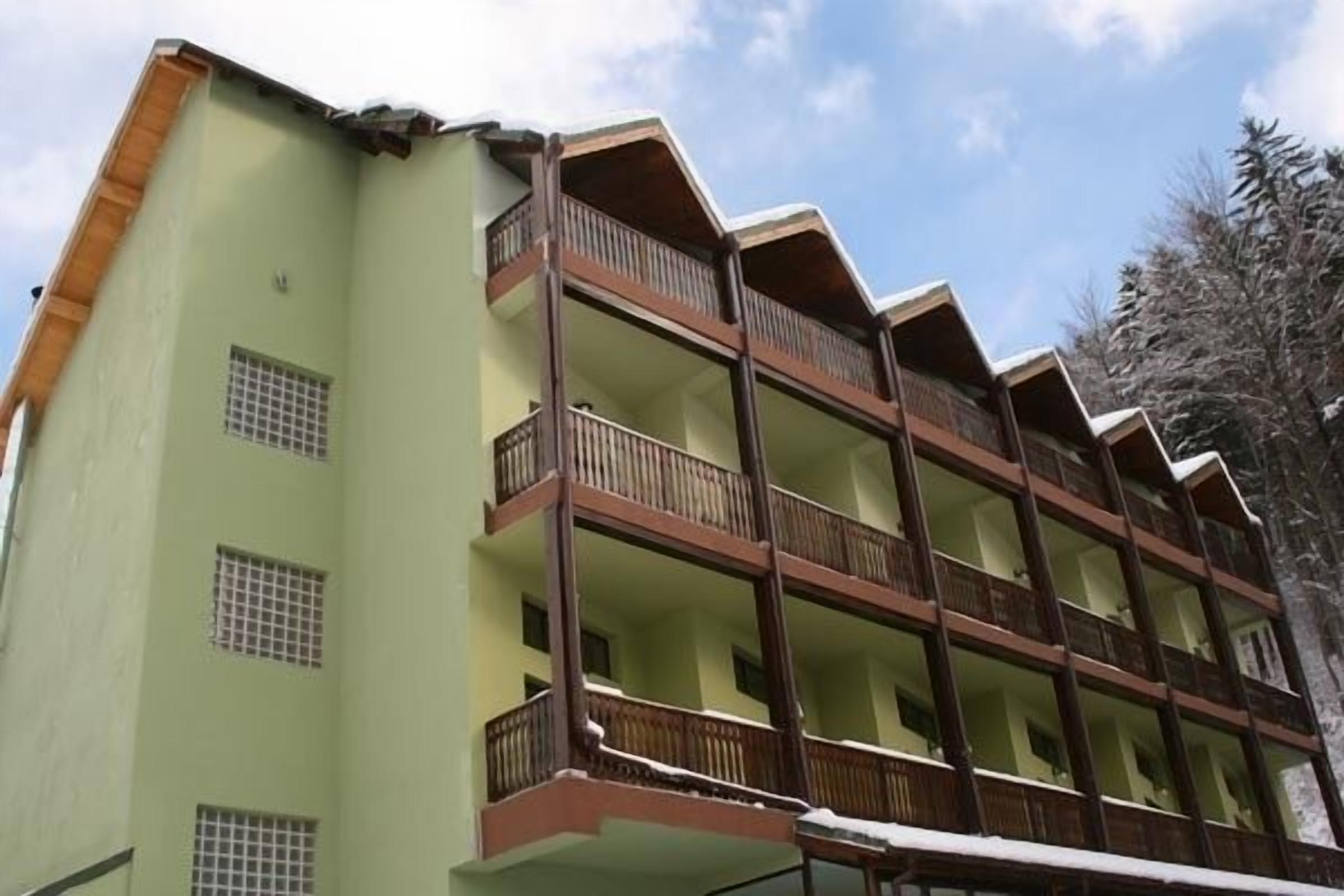 Um edifício com várias andares, varandas e fachada verde.