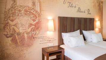 Quarto de hotel com um mural grande, uma cama com roupa branca e duas luminárias de cabeceira.