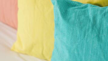 Cama com três almofadas em cores diferentes.