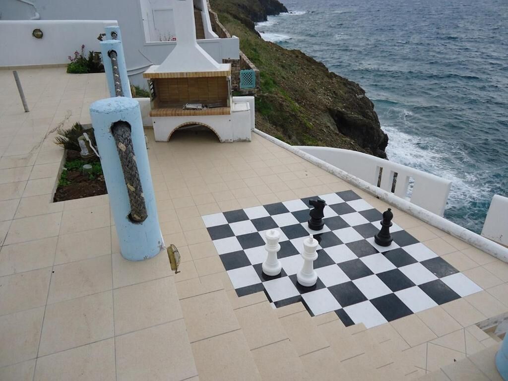 Um tabuleiro de xadrez montado em um terraço com vista para o oceano.