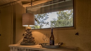 Cozinha rústica com abajur de pedra, garrafa de vinho e copos em bancada de madeira.