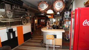 Uma área de bar com balcão, banquetas e uma decoração de carro antigo.