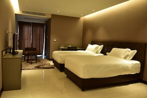 Quarto de hotel com duas camas, uma escrivaninha e uma cadeira.