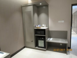 Quarto de hotel moderno com roupeiro embutido, um pequeno espaço para sentar e micro-ondas.