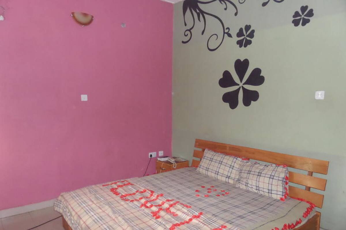 Quarto com uma cama, parede rosa e adesivos decorativos.
