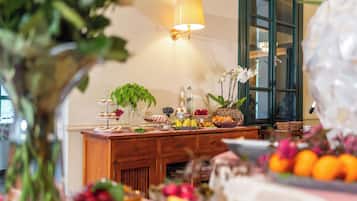 Uma mesa de buffet com diversos alimentos e uma luminária ao fundo.