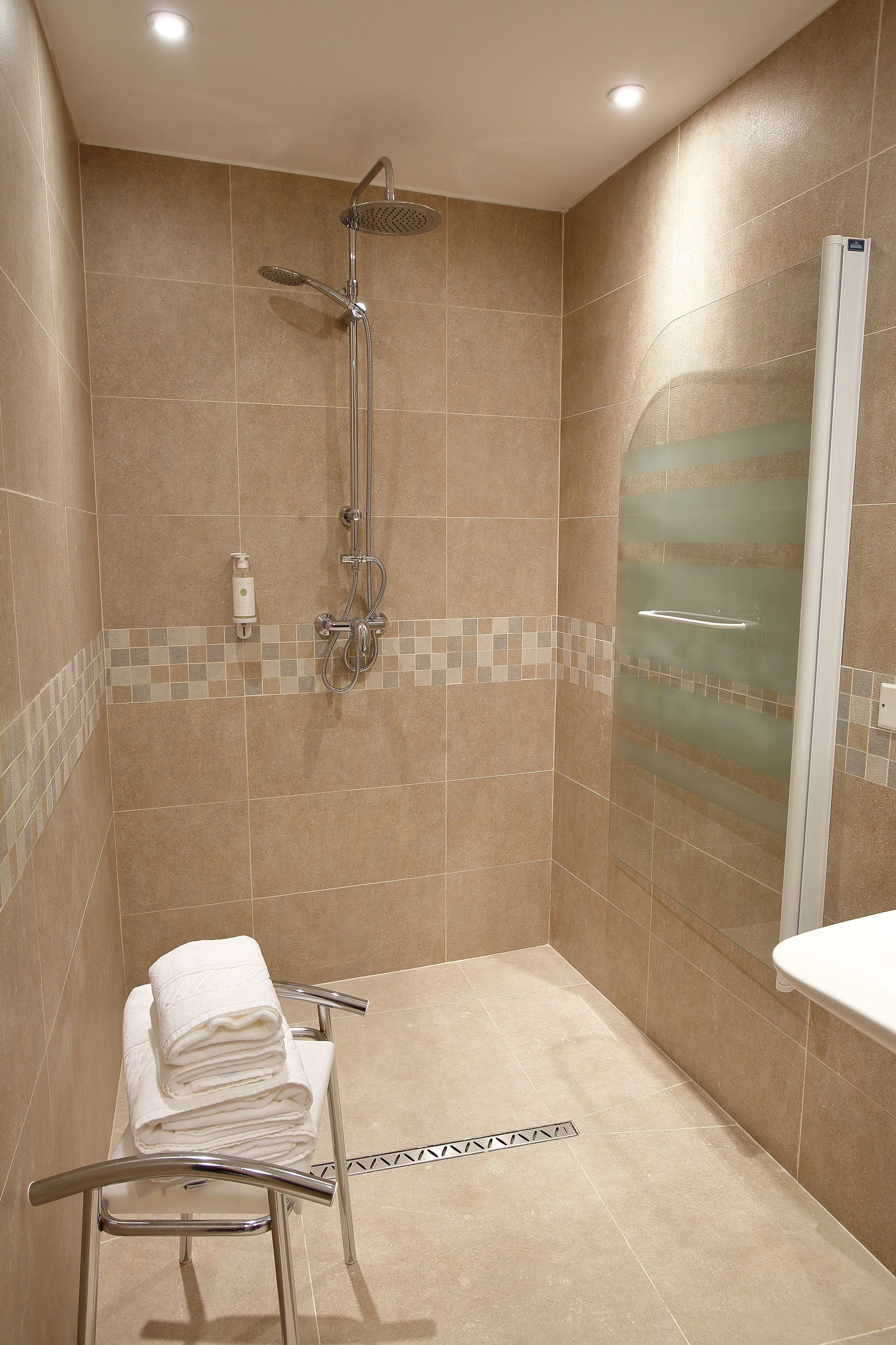 Uma casa de banho moderna com chuveiro, porta-toalhas e porta de vidro do chuveiro.