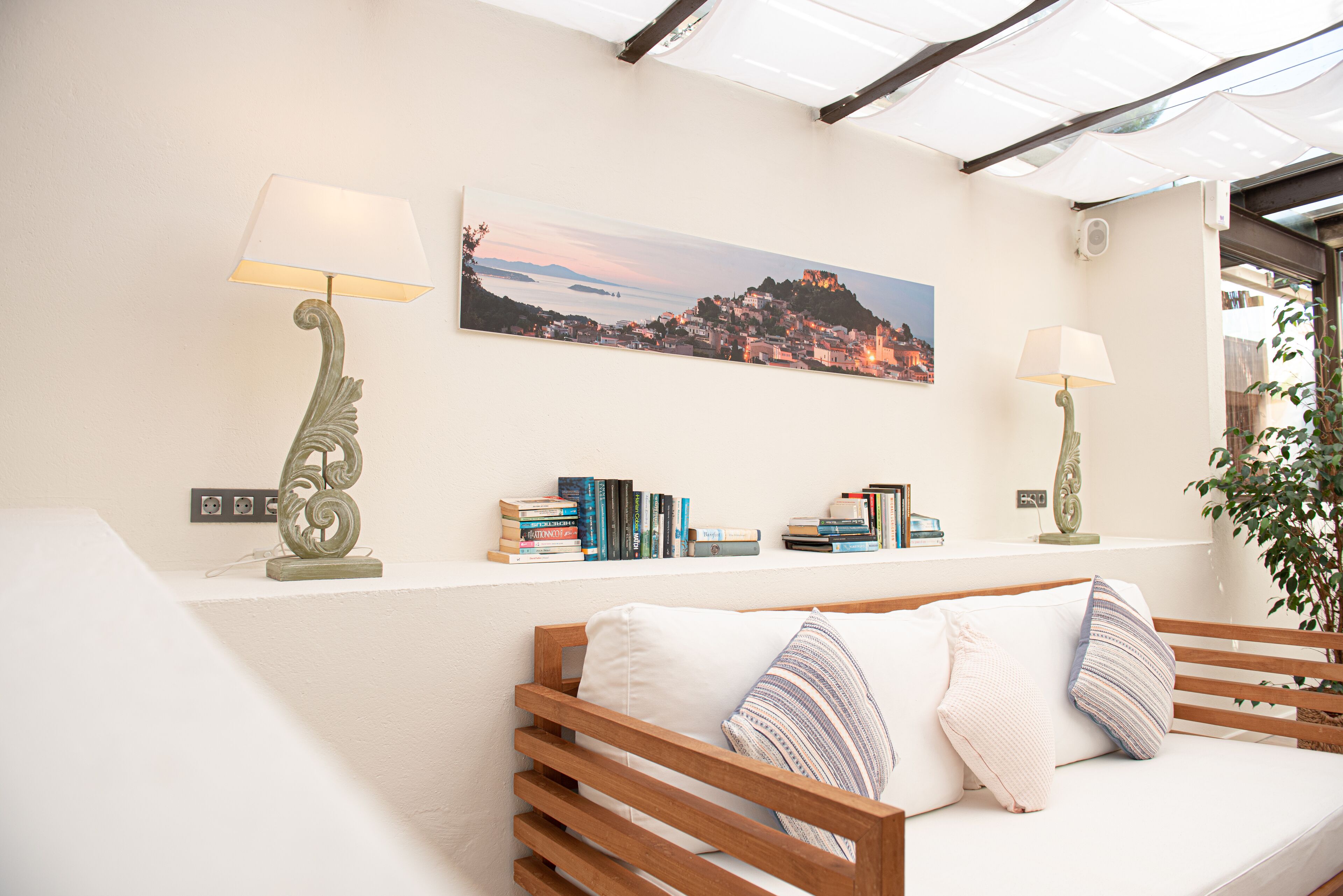 Um quarto acolhedor com um banco de madeira, uma prateleira na parede com livros e uma pintura de paisagem.