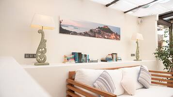 Um quarto acolhedor com um banco de madeira, uma prateleira na parede com livros e uma pintura de paisagem.