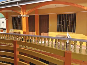 Um edifício amarelo com varanda, porta marrom e janelas com grades.