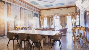 Um quarto espaçoso com uma grande mesa de jantar, cadeiras elegantes e um lustre.