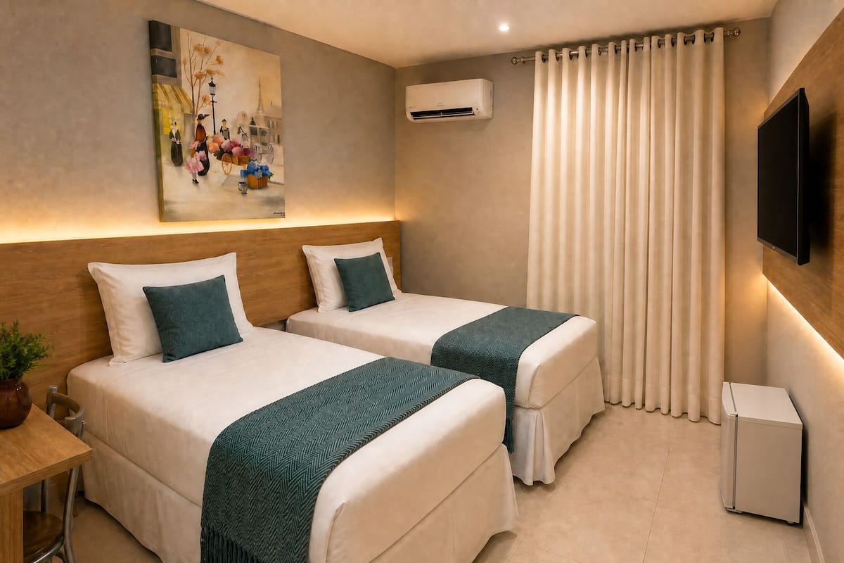 Quarto de hotel com duas camas, um quadro na parede, ar condicionado, televisão e frigorífico.
