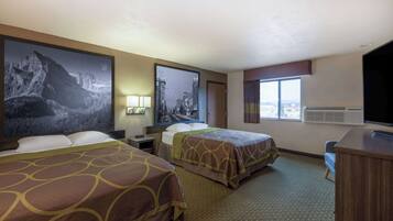 Quarto de hotel com duas camas, uma escrivaninha, televisão e amplas janelas com vista.