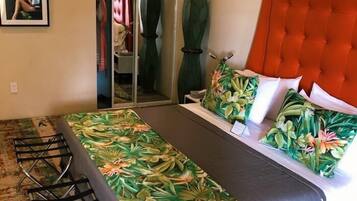 Um quarto com cama, uma cadeira, um espelho e ar condicionado.
